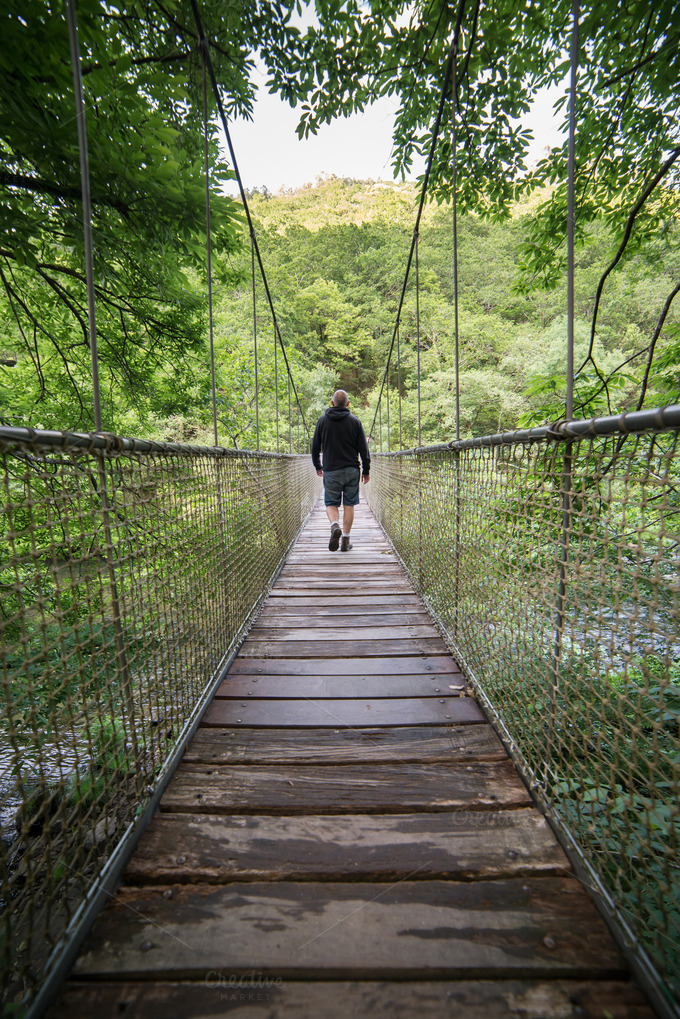 Man crossing a suspension bridge ~ People Photos on Creative Market